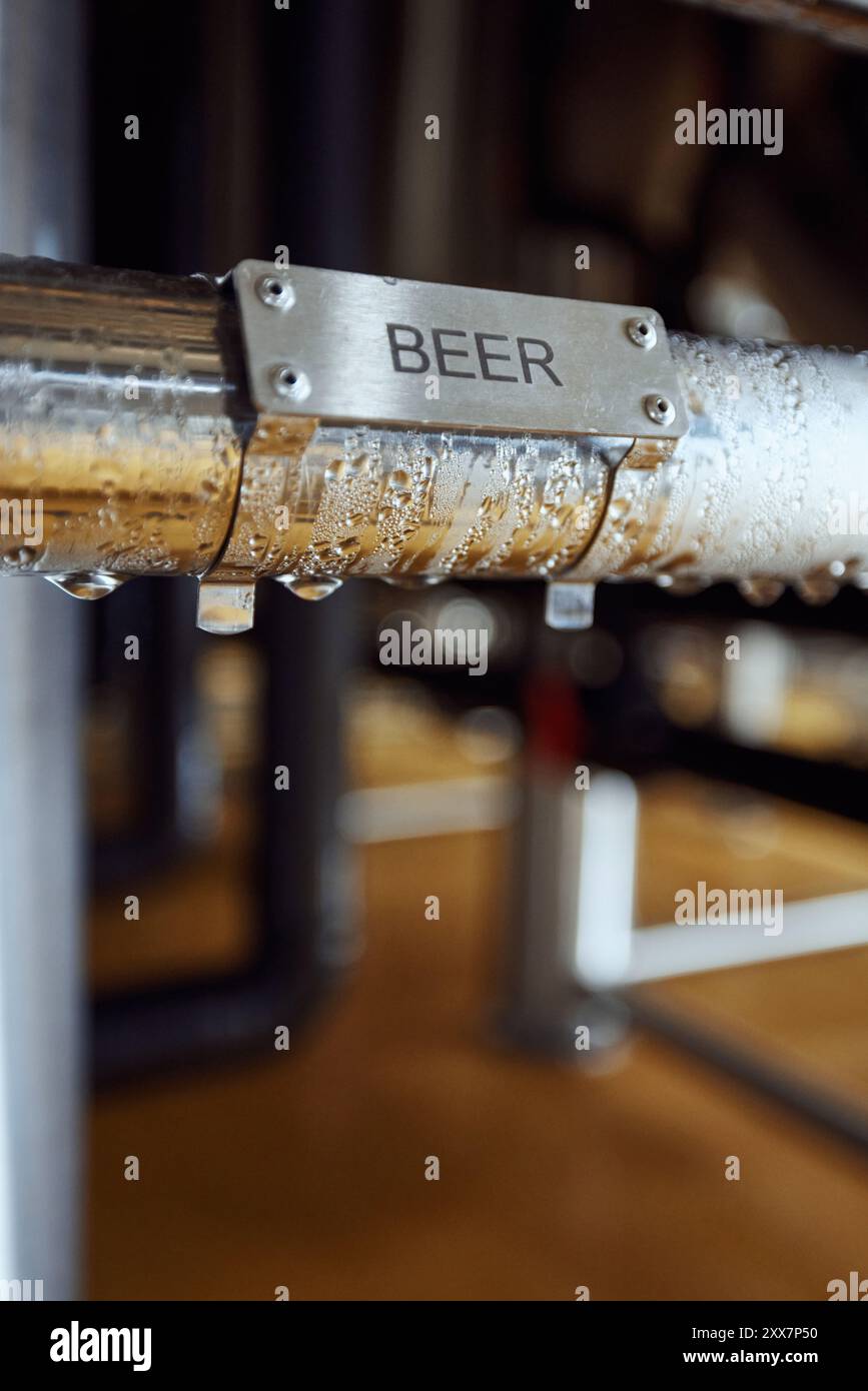Close-up of stainless steel pipe with metal plate labeled BEER, with ...