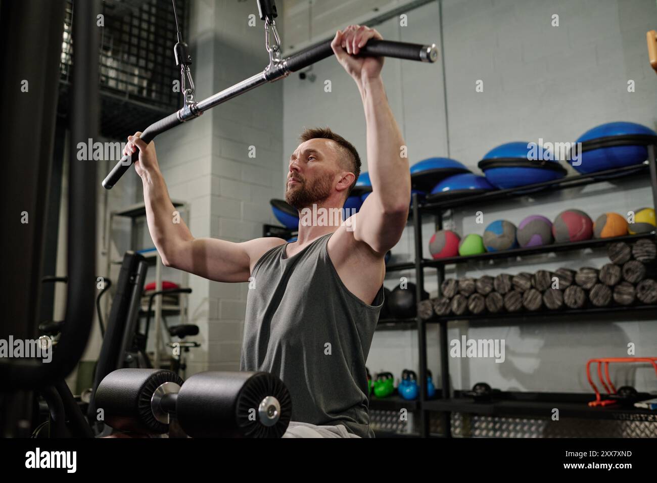 Professional Caucasian athlete using weight machine to bulk muscle ...