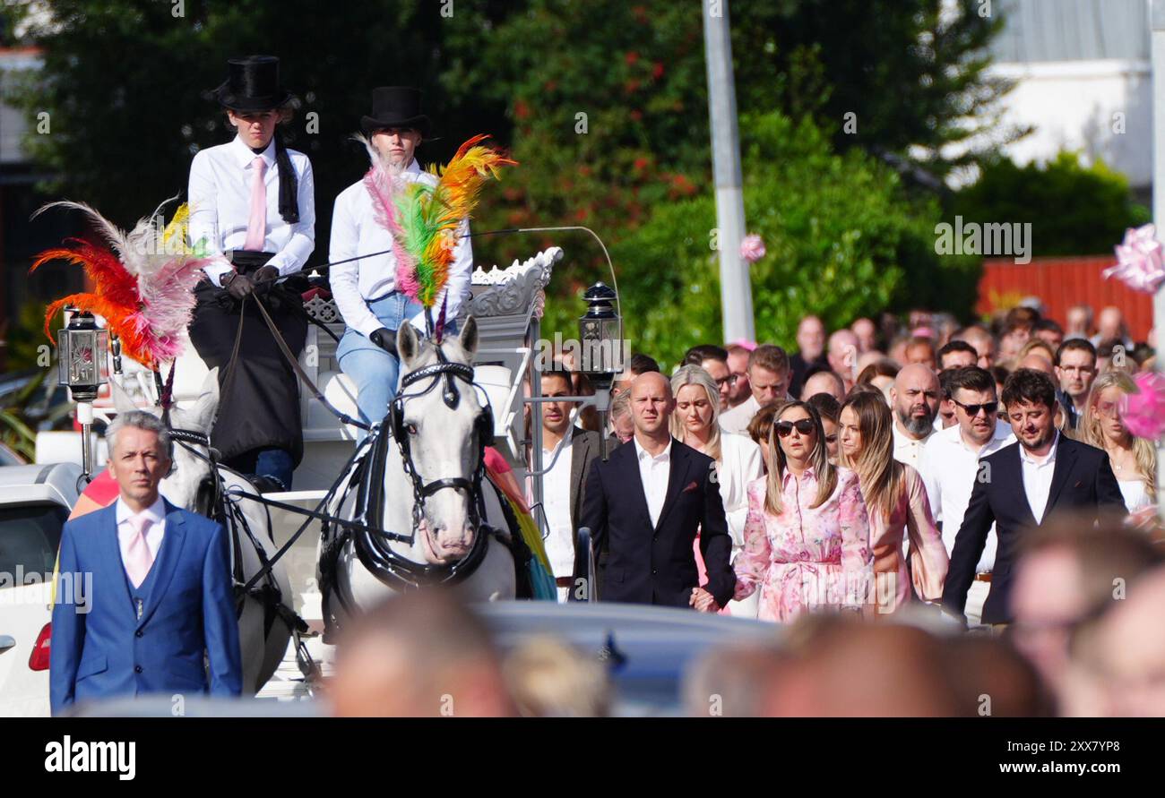 Mourners walk behind the horse-drawn carriage carrying the coffin of ...
