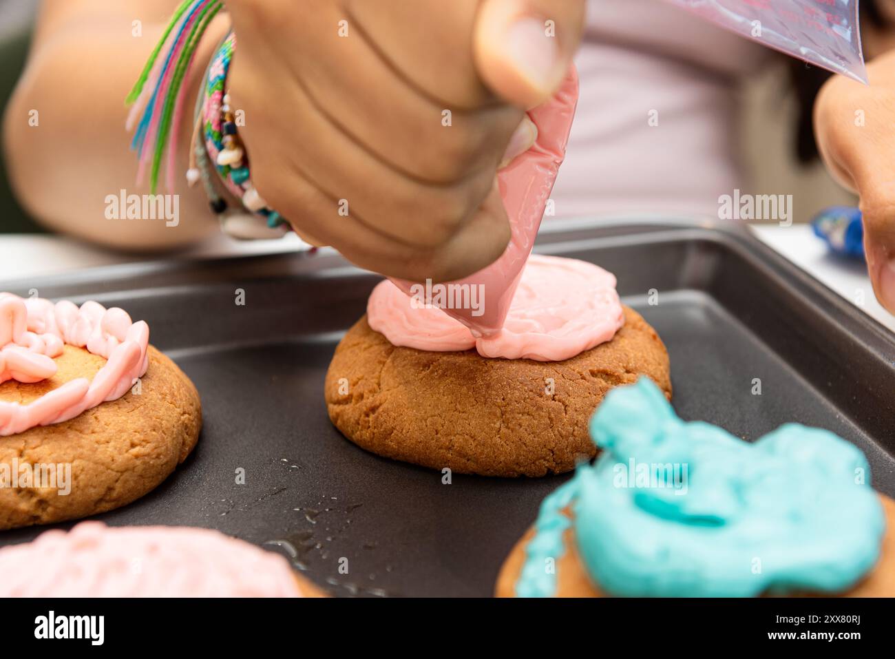 Close-up of hands frosting cookies with pink and blue icing Stock Photo ...