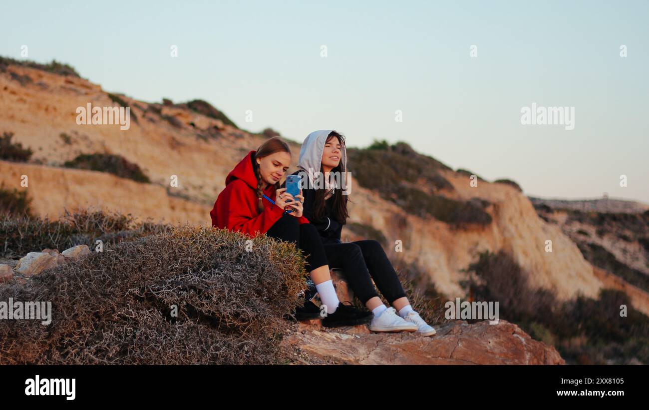Two friends sitting on a rocky hillside Stock Photo - Alamy