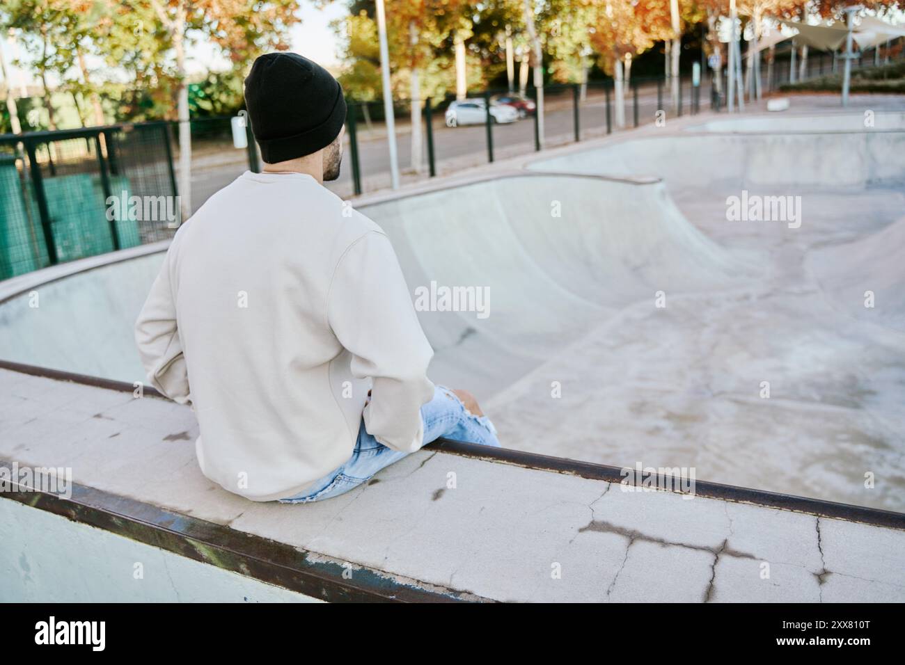 young skateboarder sitting on the kerb of an empty skatepark Stock ...