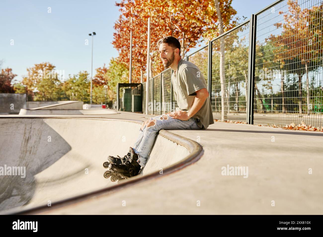 young skateboarder sitting on the kerb of an empty skatepark Stock ...