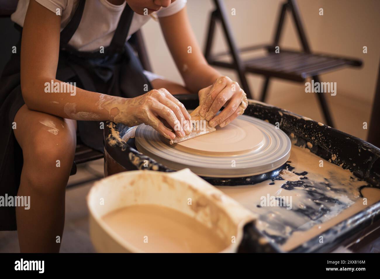 Girl is using a pottery scrapper to smooth the edges of a clay p Stock ...