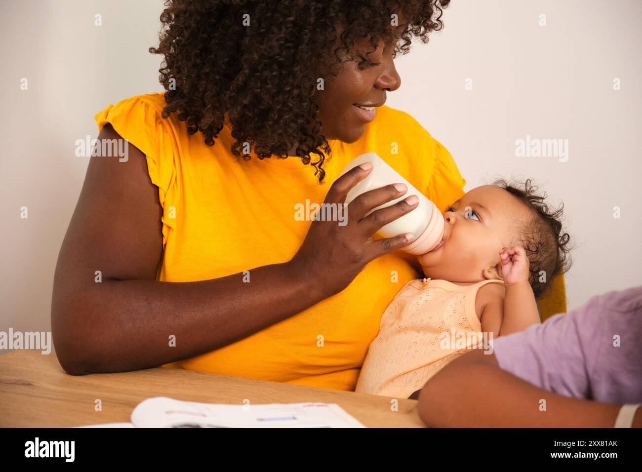 Loving mother feeding her baby with milk formula at home Stock Photo ...