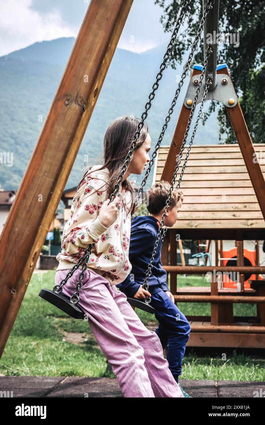 Two cute kids swinging on a swing Stock Photo - Alamy