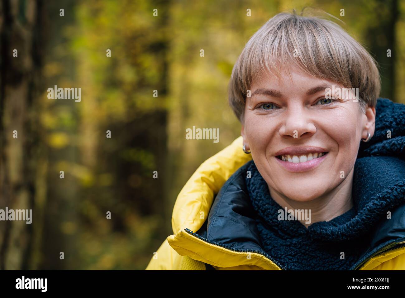 Smiling blonde woman enjoying autumn forest walk Stock Photo - Alamy