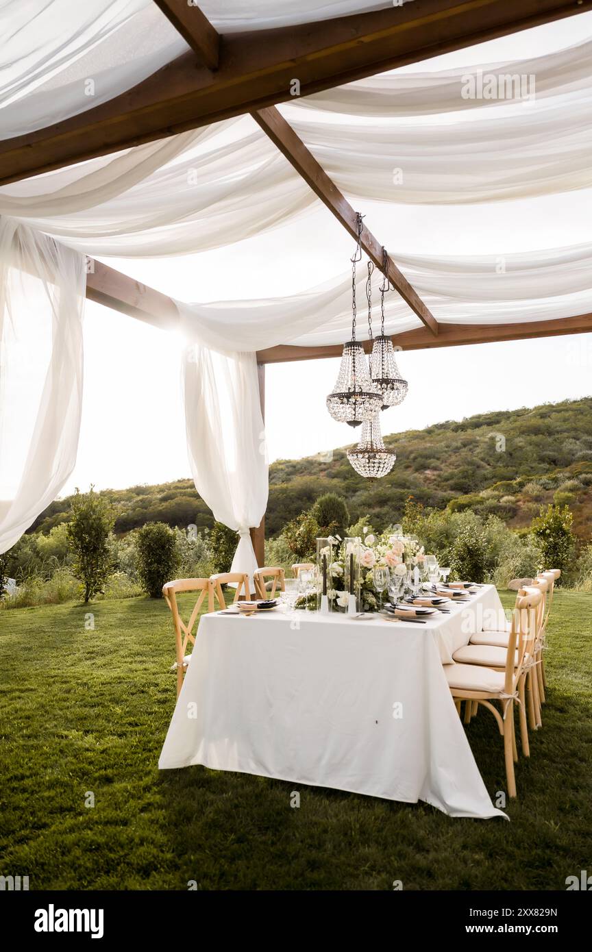 Outdoor wedding reception with draped fabric and chandeliers vertical ...
