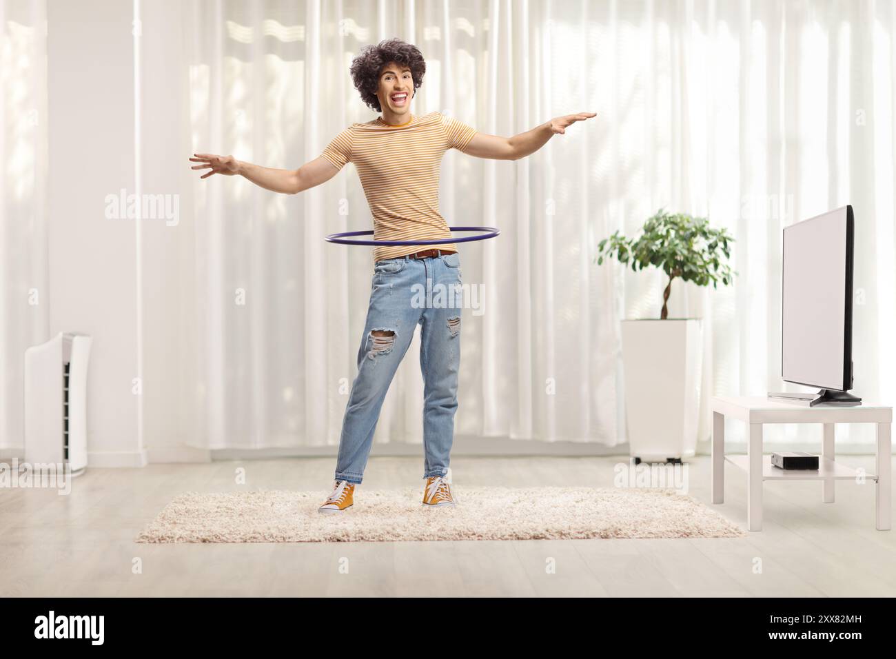 Happy young man spinning a hula hoop in a room Stock Photo - Alamy