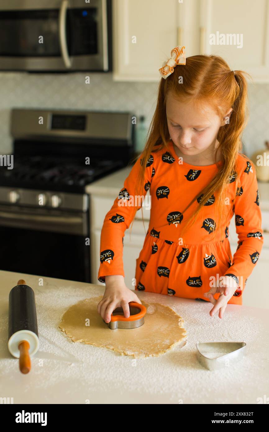 Redhead girl making sugar cookies in an orange halloween dress Stock ...