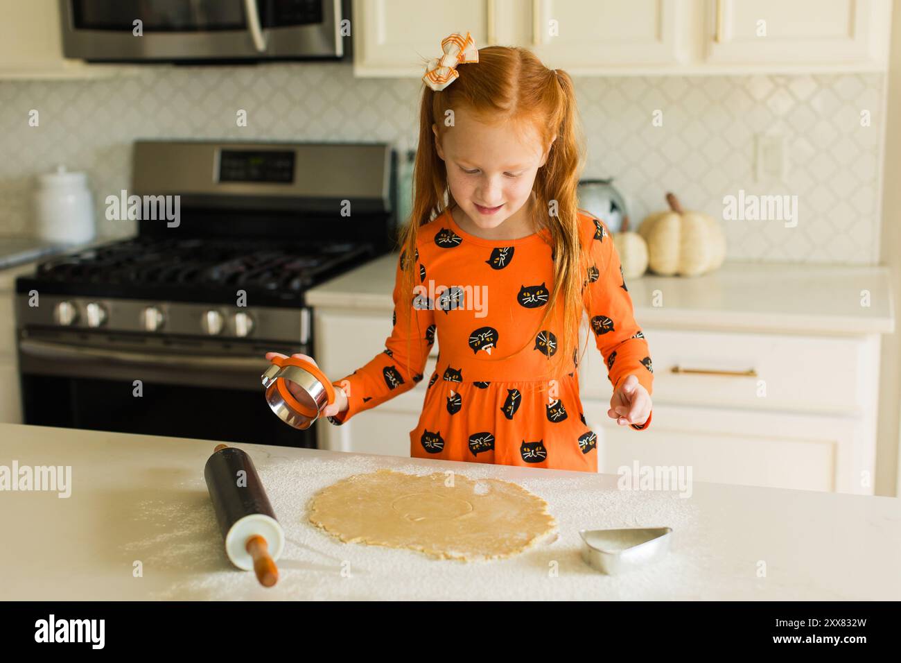 Redhead girl making sugar cookies, wearing am orange dress Stock Photo ...