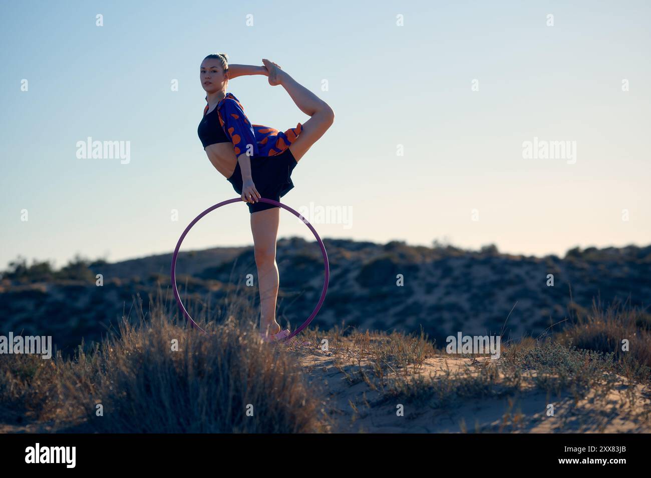Performer executes a graceful pose on one leg while holding a hoop ...