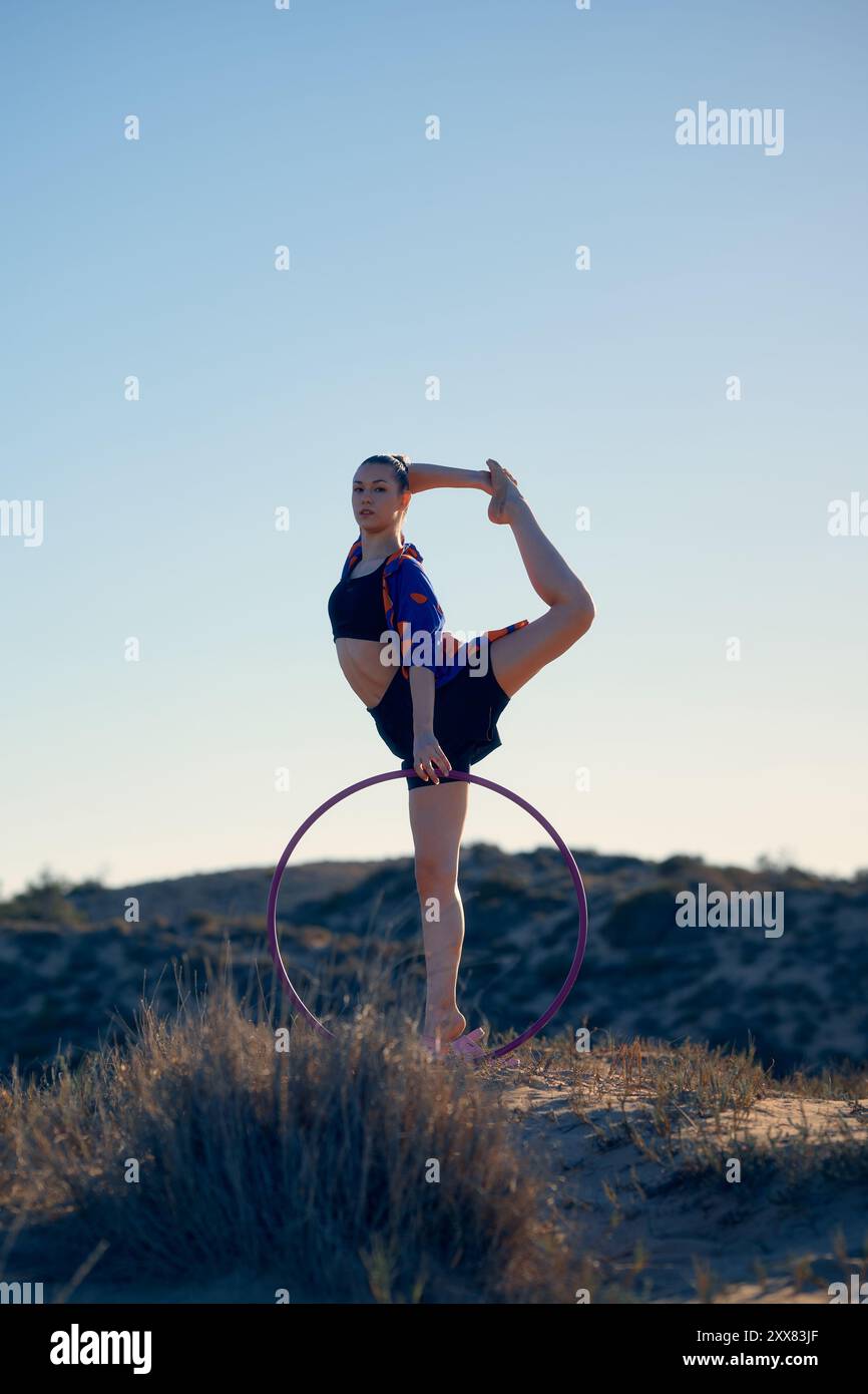 Performer executes a graceful pose on one leg while holding a hoop ...