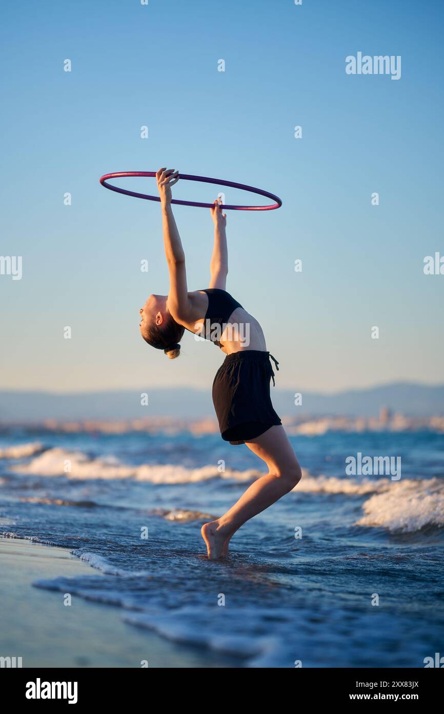 Woman hula hooping near the shore during sunset at the beach Stock ...