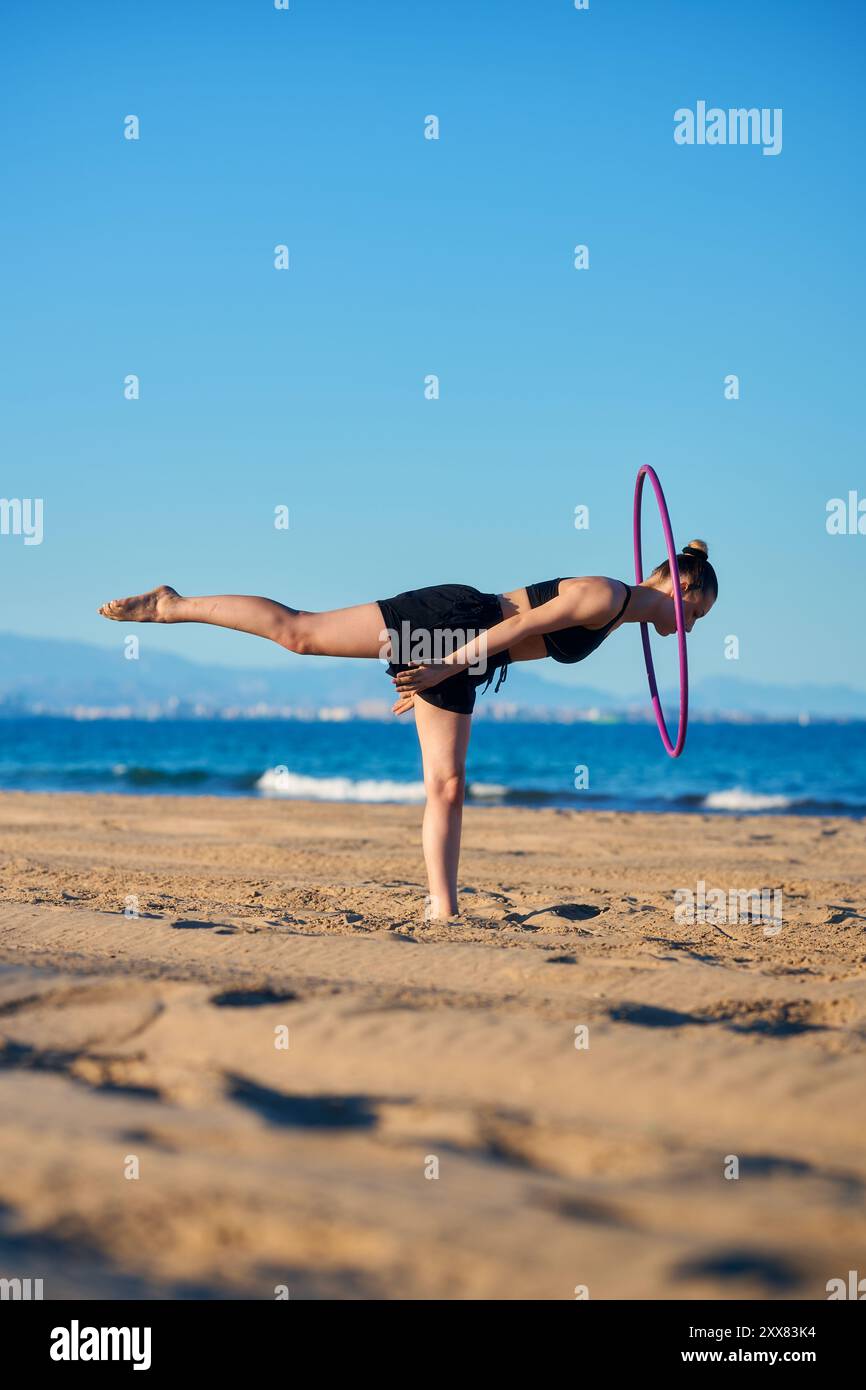 A woman balances on one leg while performing with a hula hoop Stock ...