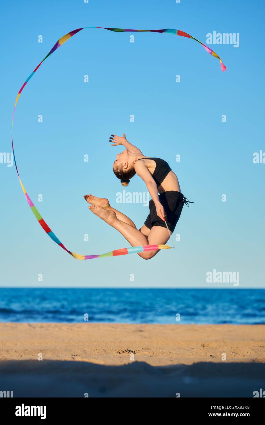 Young woman performing rhythmic gymnastics with ribbon on a beach Stock ...