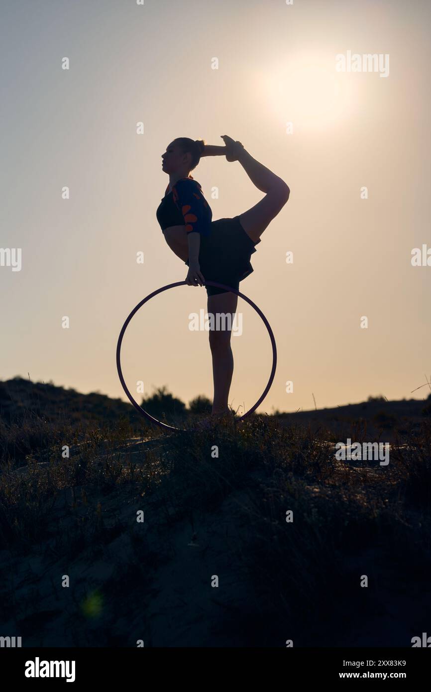 Performer executes a graceful pose on one leg while holding a hoop ...