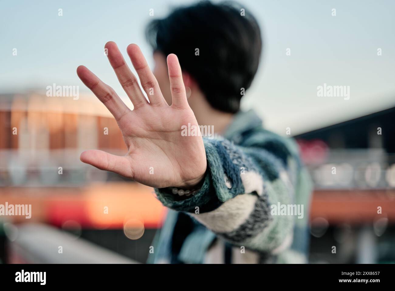 young asian man covering his face in a stop sign. young celebrity ...