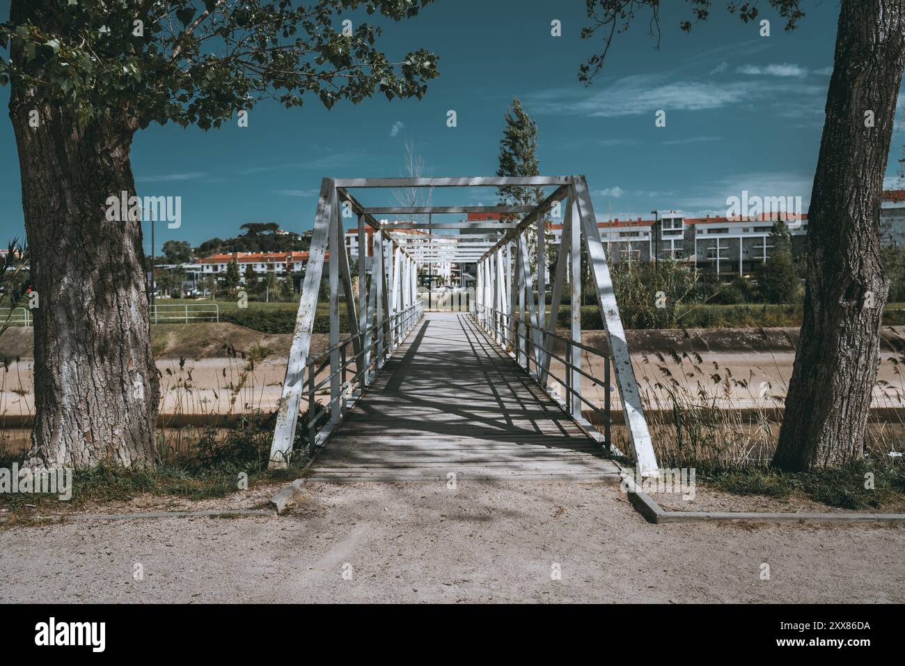 A wide-angle shot of a white pedestrian bridge with a metal frame ...