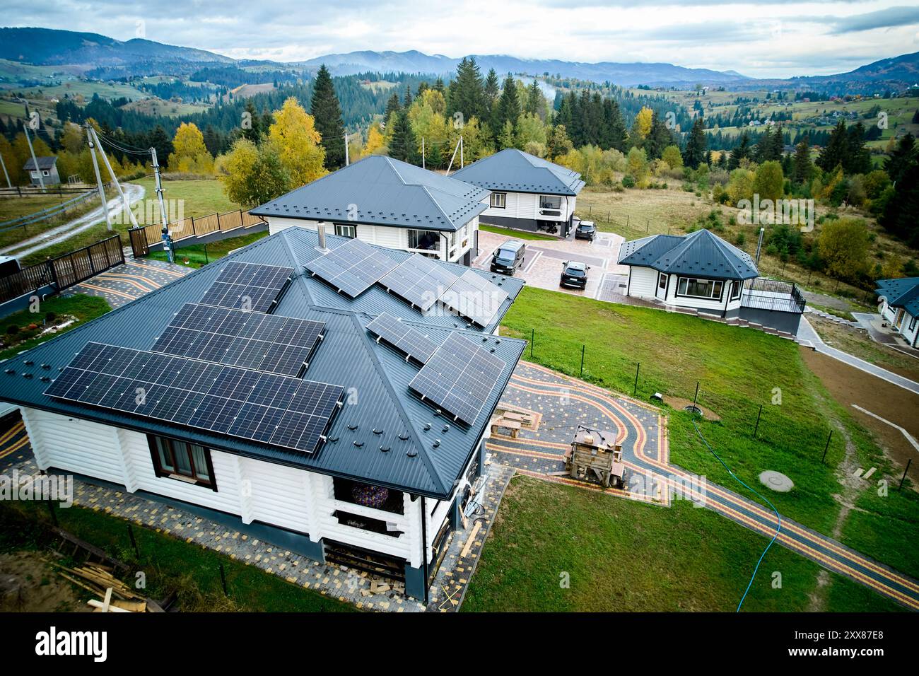 Aerial view of new modern house cottage in the mountains with solar photovoltaic panel system on ...