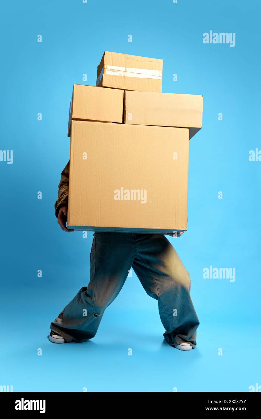 Balancing towering stack of boxes, only person's legs visible against ...