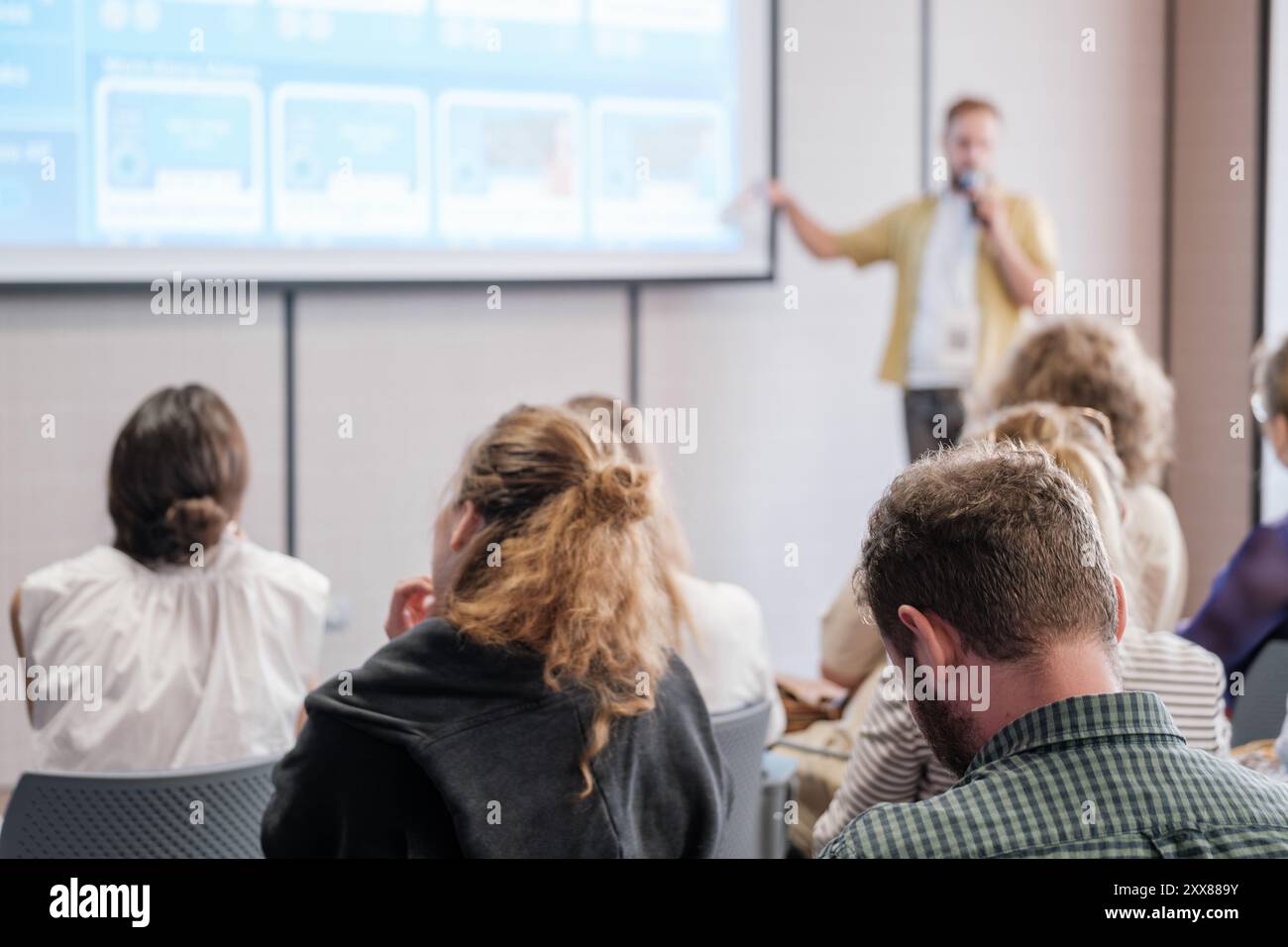 Audience engaged in business presentation with speaker and projection ...