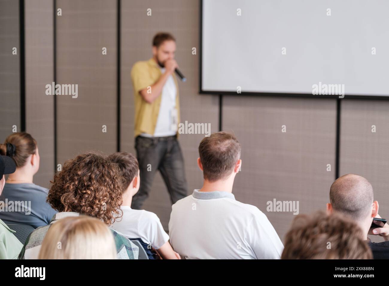 Speaker delivering presentation to attentive audience in modern ...