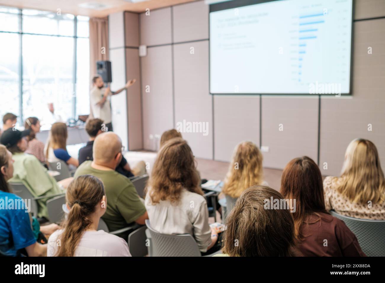 Speaker delivers presentation to attentive audience in bright modern ...