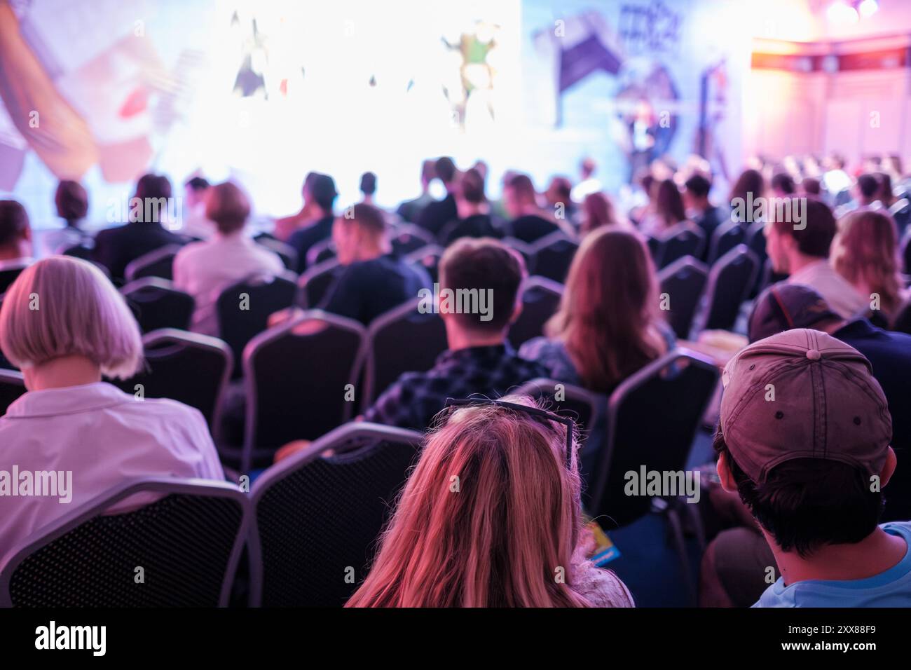 Large group of people seated in rows focused on presentation at ...