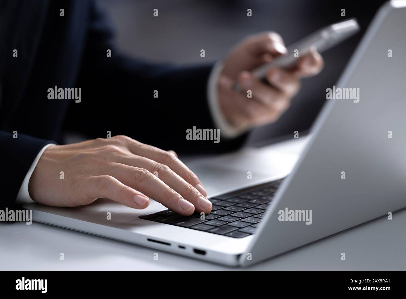 The businessman works on his laptop while simultaneously checking his ...