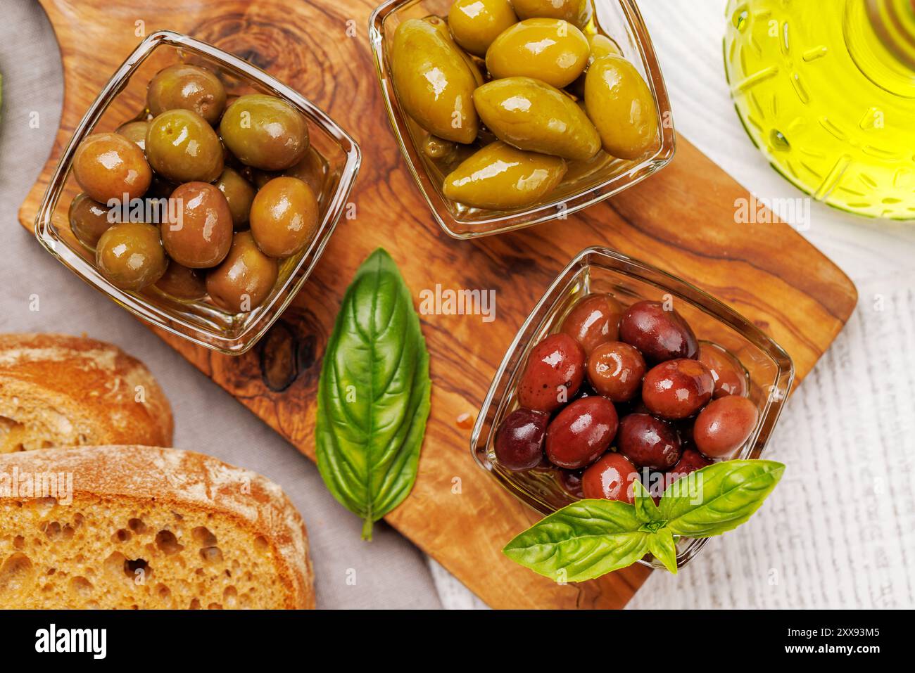 An assortment of various olives presented in a bowl and olive oil ...