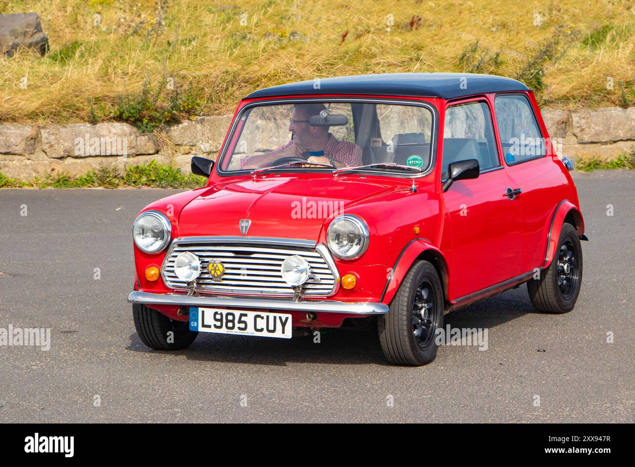 Classic red Mini Cooper parked on a road with greenery in the ...