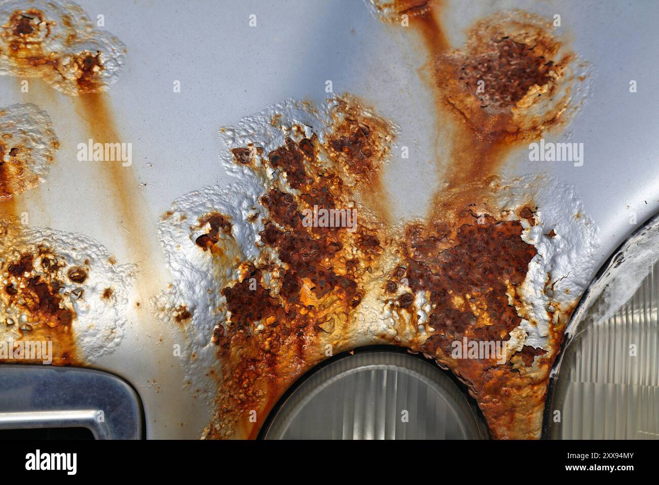 Rusty car hood next to the headlights. Weather corrosion damage in ...
