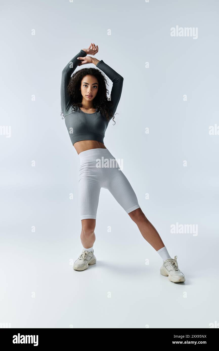 A young African American woman stretches her arms overhead while ...