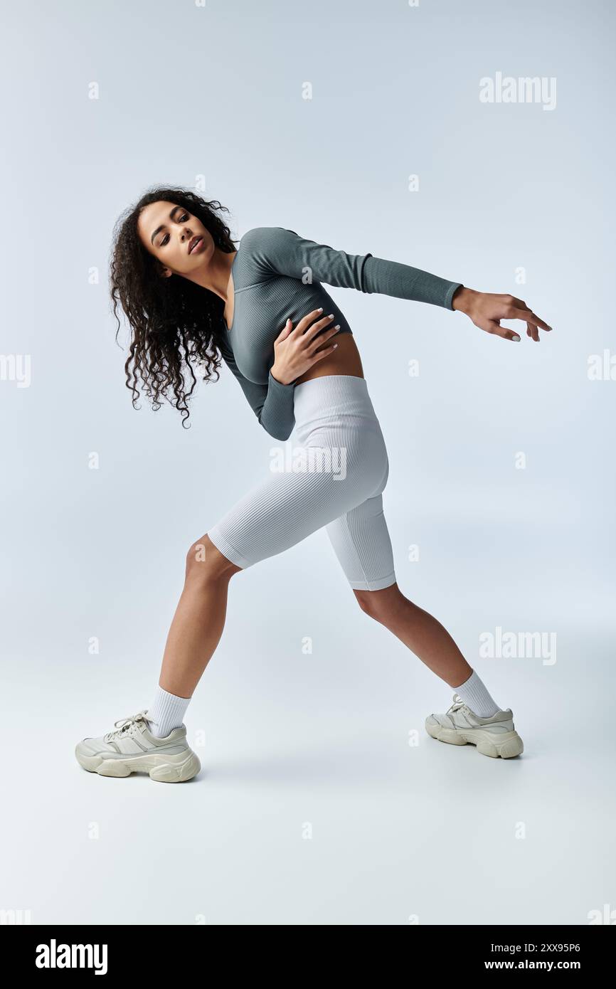 A young woman in athletic wear stretches with a graceful pose against a ...
