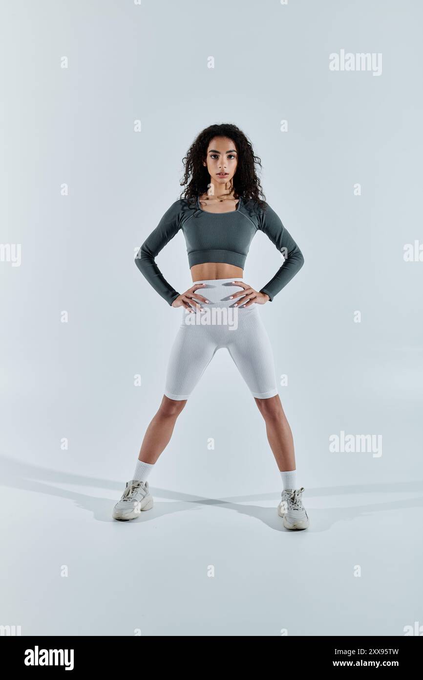 A young African American woman stands with hands on hips, showcasing her strength and athletic ...