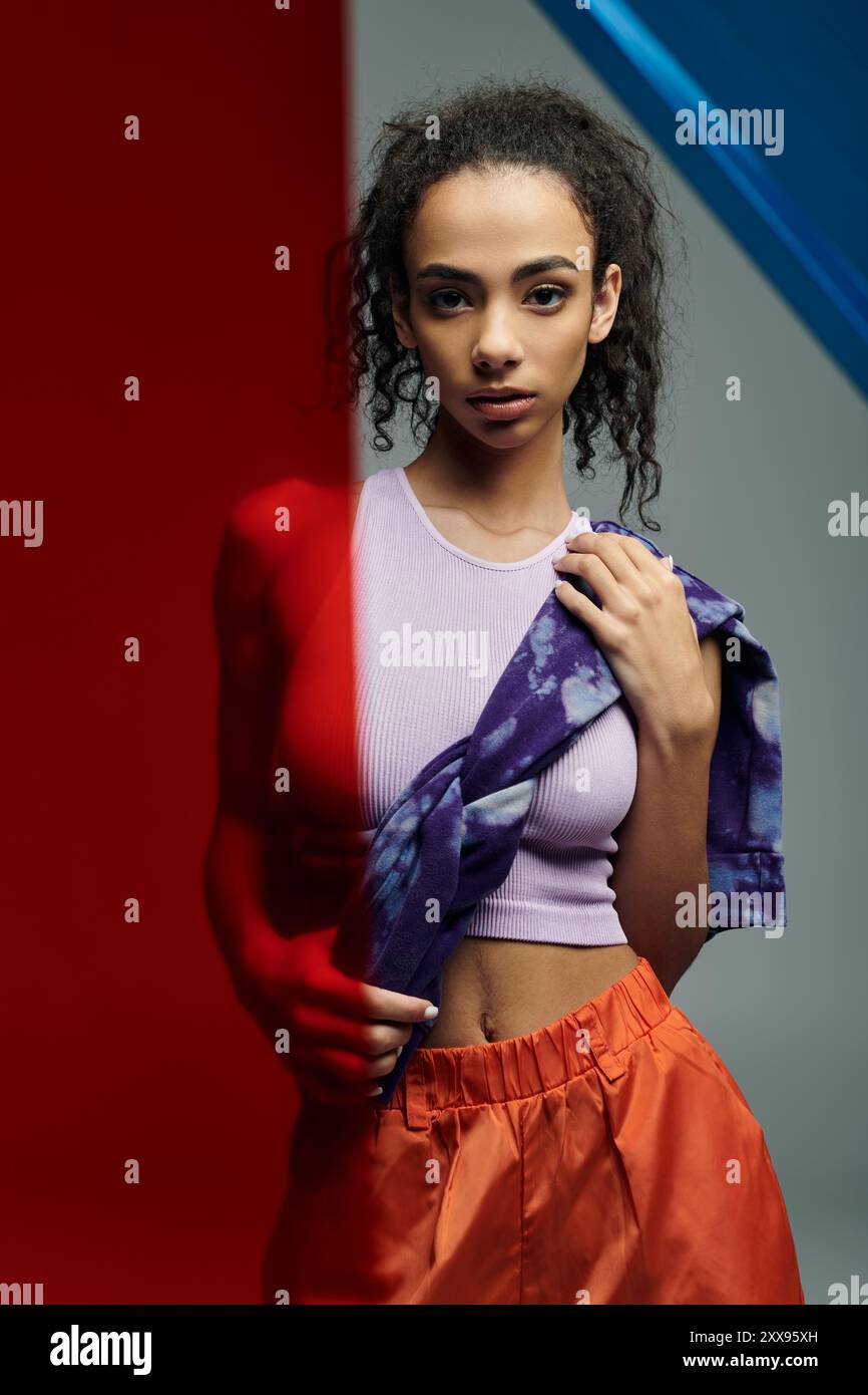 A young woman in athletic wear poses with a colorful backdrop ...