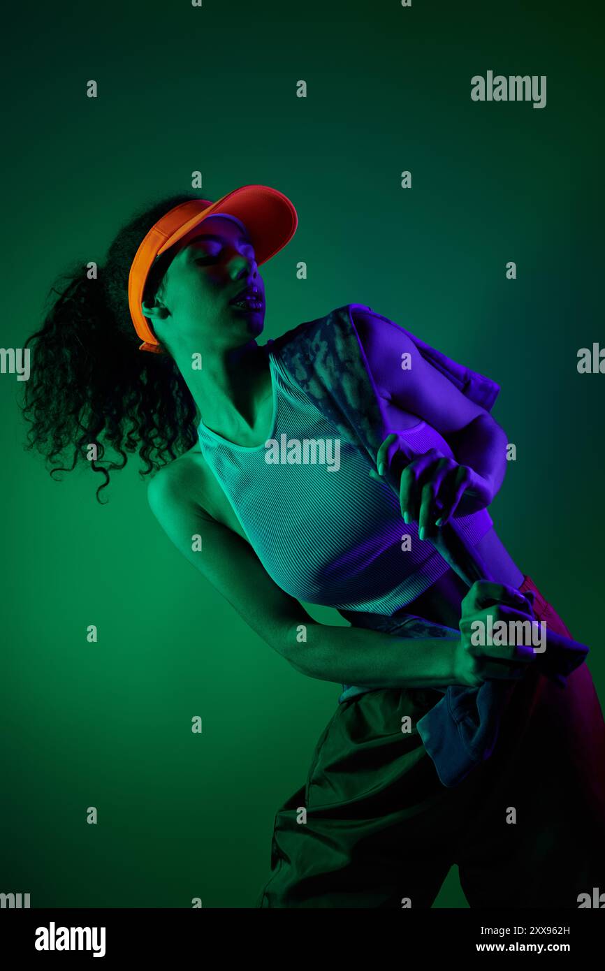 A young woman poses in a studio with neon lights, wearing a visor and a ...