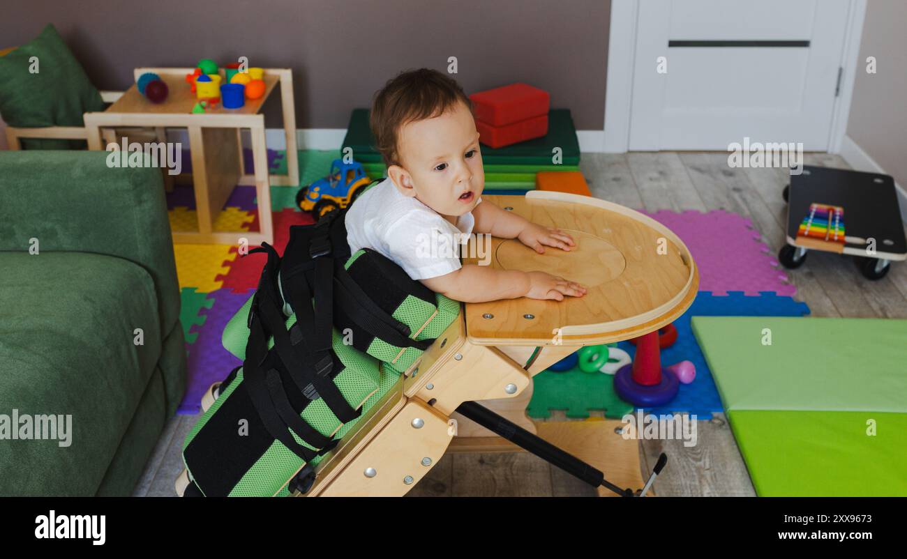 Handsome little boy with damage to CNS is standing in a verticalizer ...