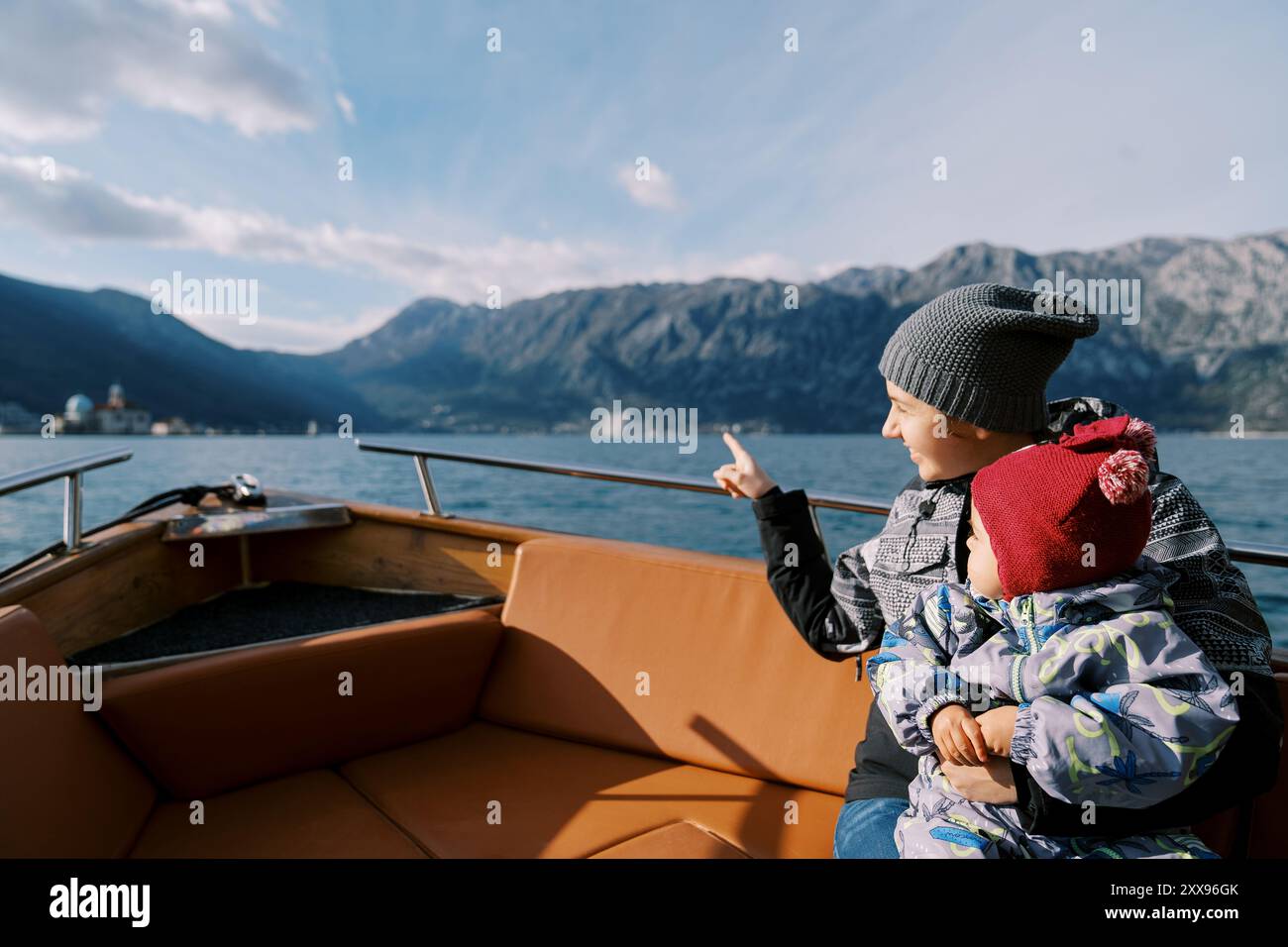 Mom with a small child in her arms floats in a boat and points to the ...