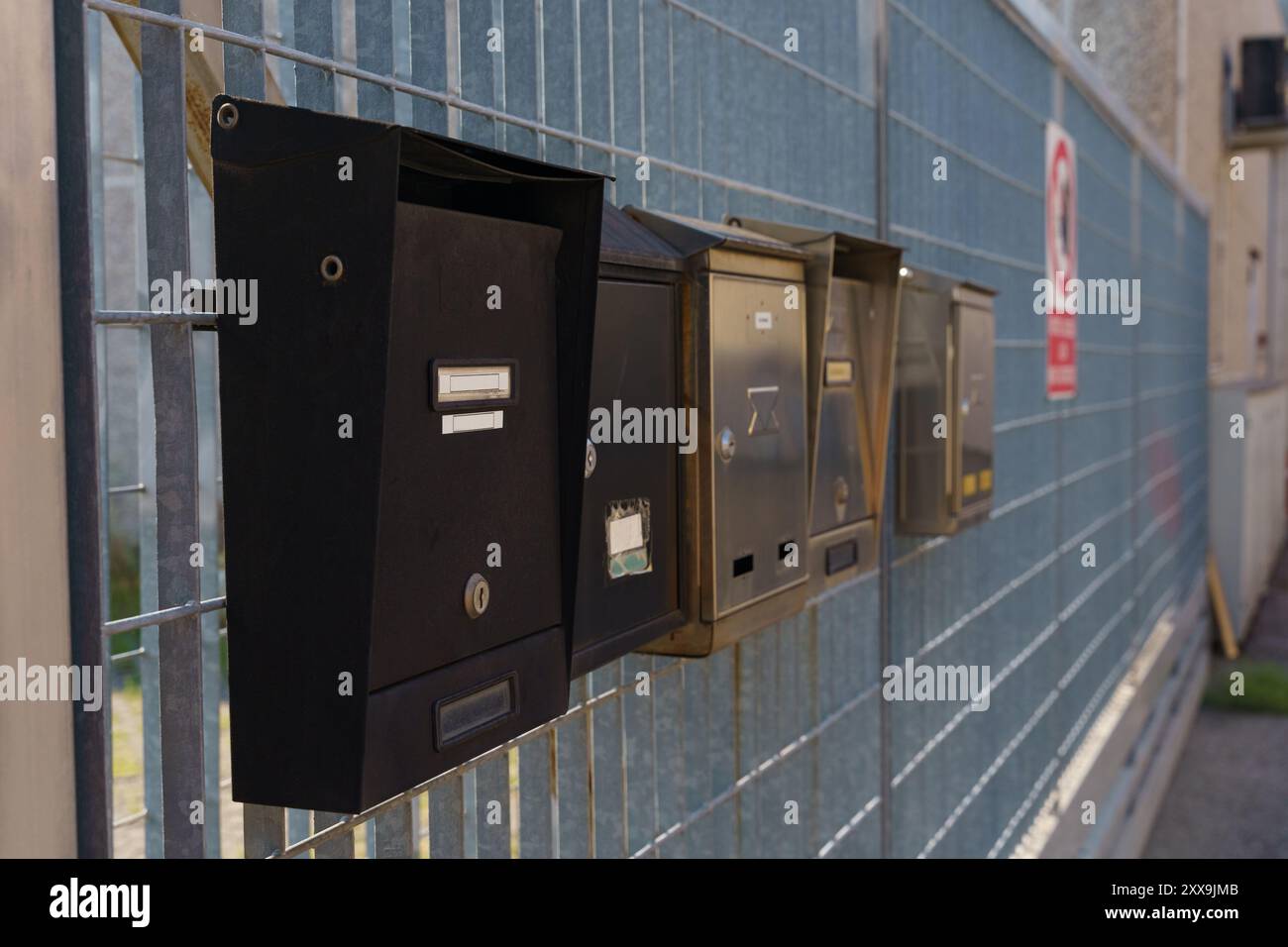 Four mailboxes of different sizes and colors are mounted on a blue ...