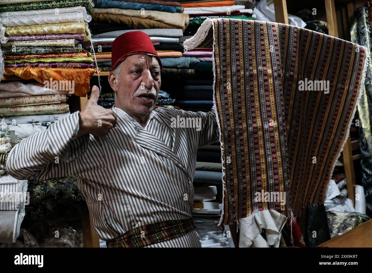 Jerusalem textile merchant Bilal Abu Khalaf stands in his shop in the Old City’s Christian ...