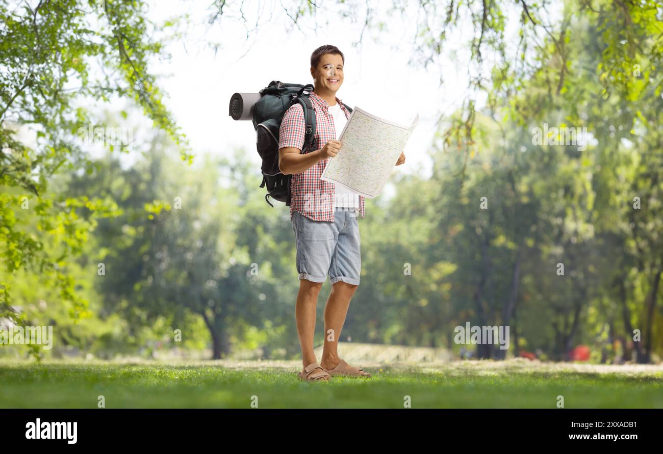 Smiling male tourist with a backpack reading a map in a park Stock ...