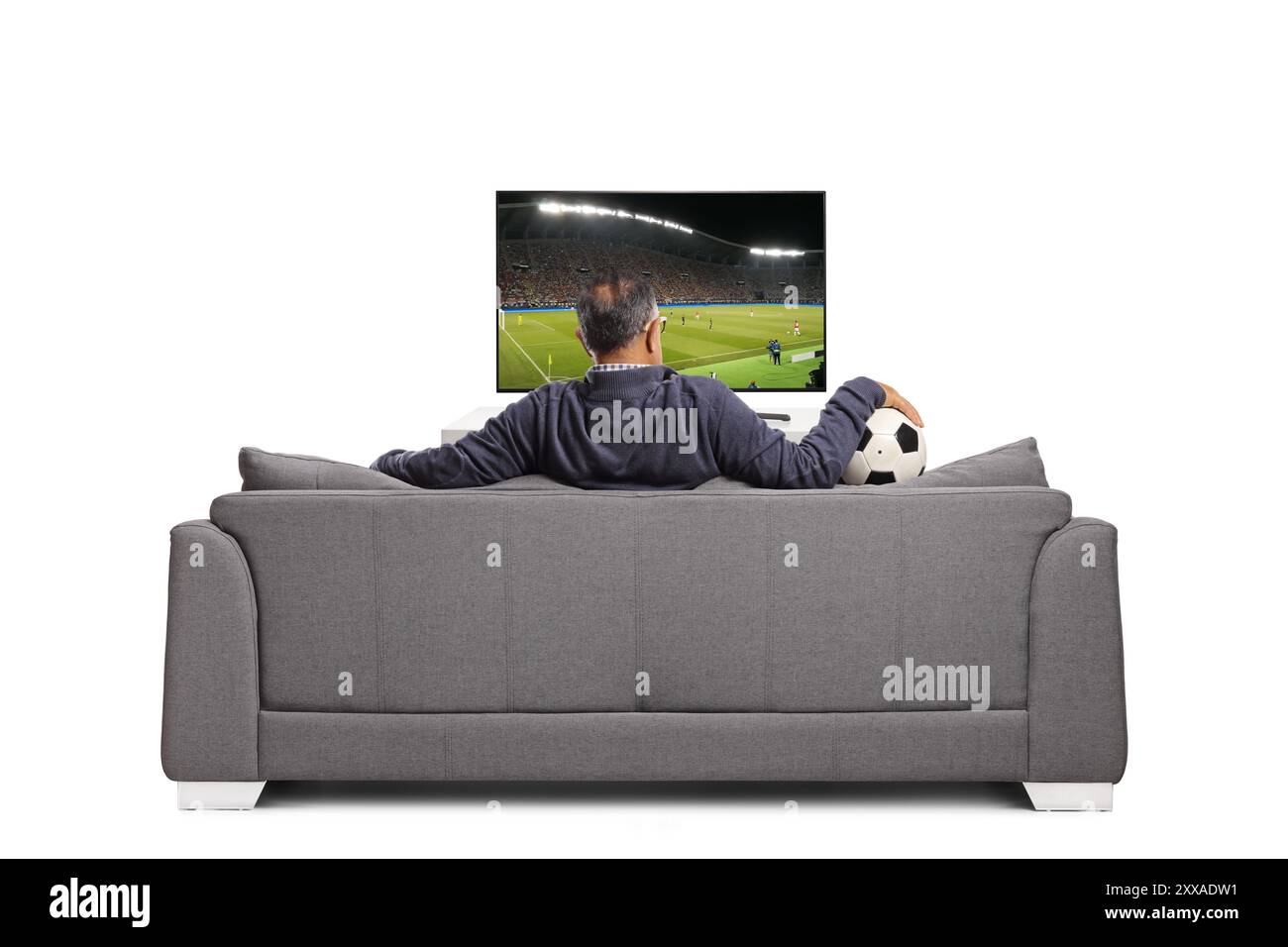 Rear view shot of a man watching football on telly and sitting on sofa ...