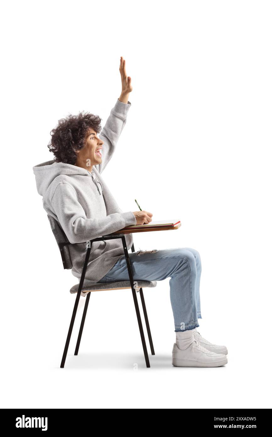 Male student sitting in a school chair and raising hand isolated on ...