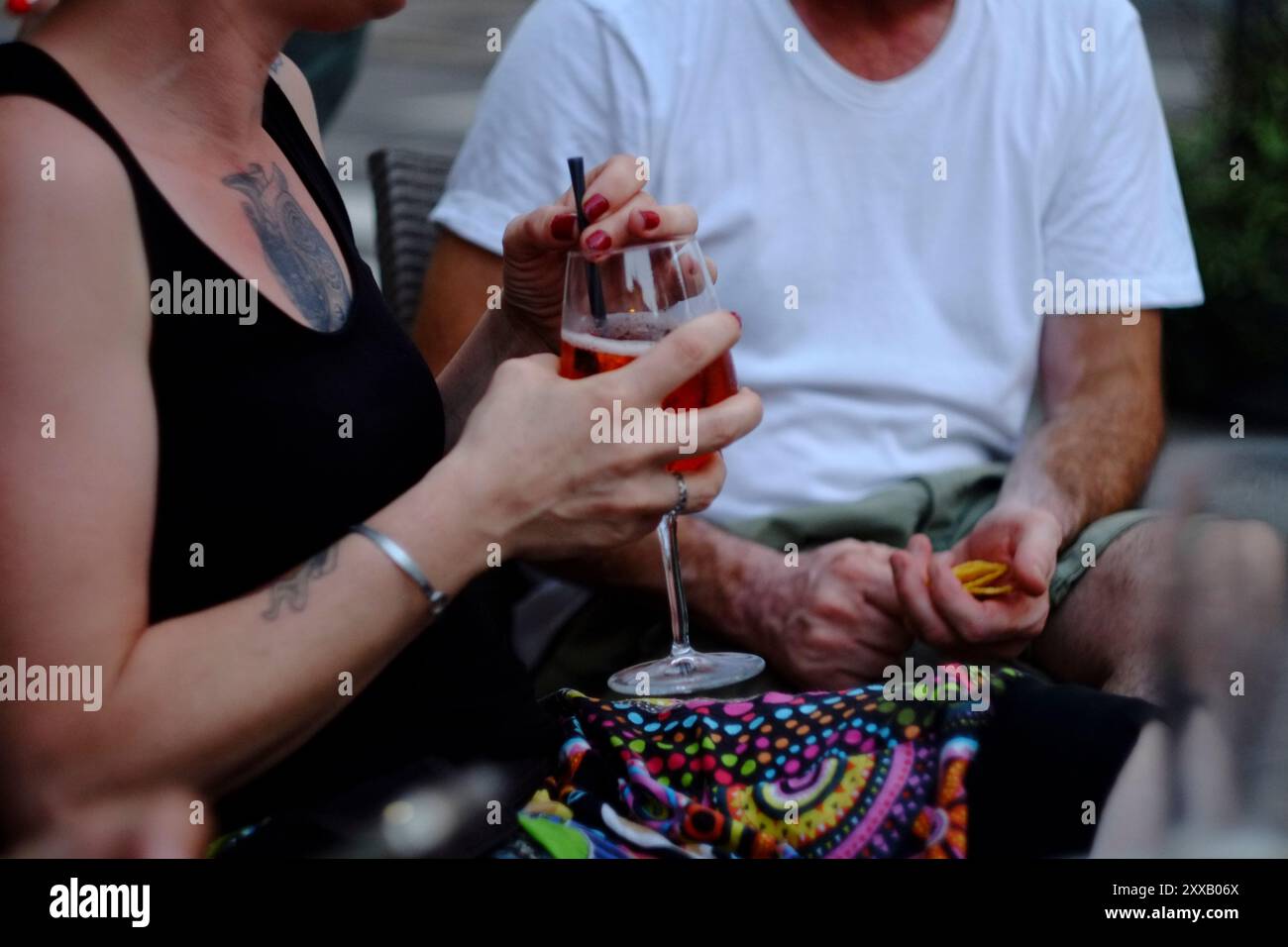 Stylish woman with tattoos sips an aperol spritz cocktail with friends ...