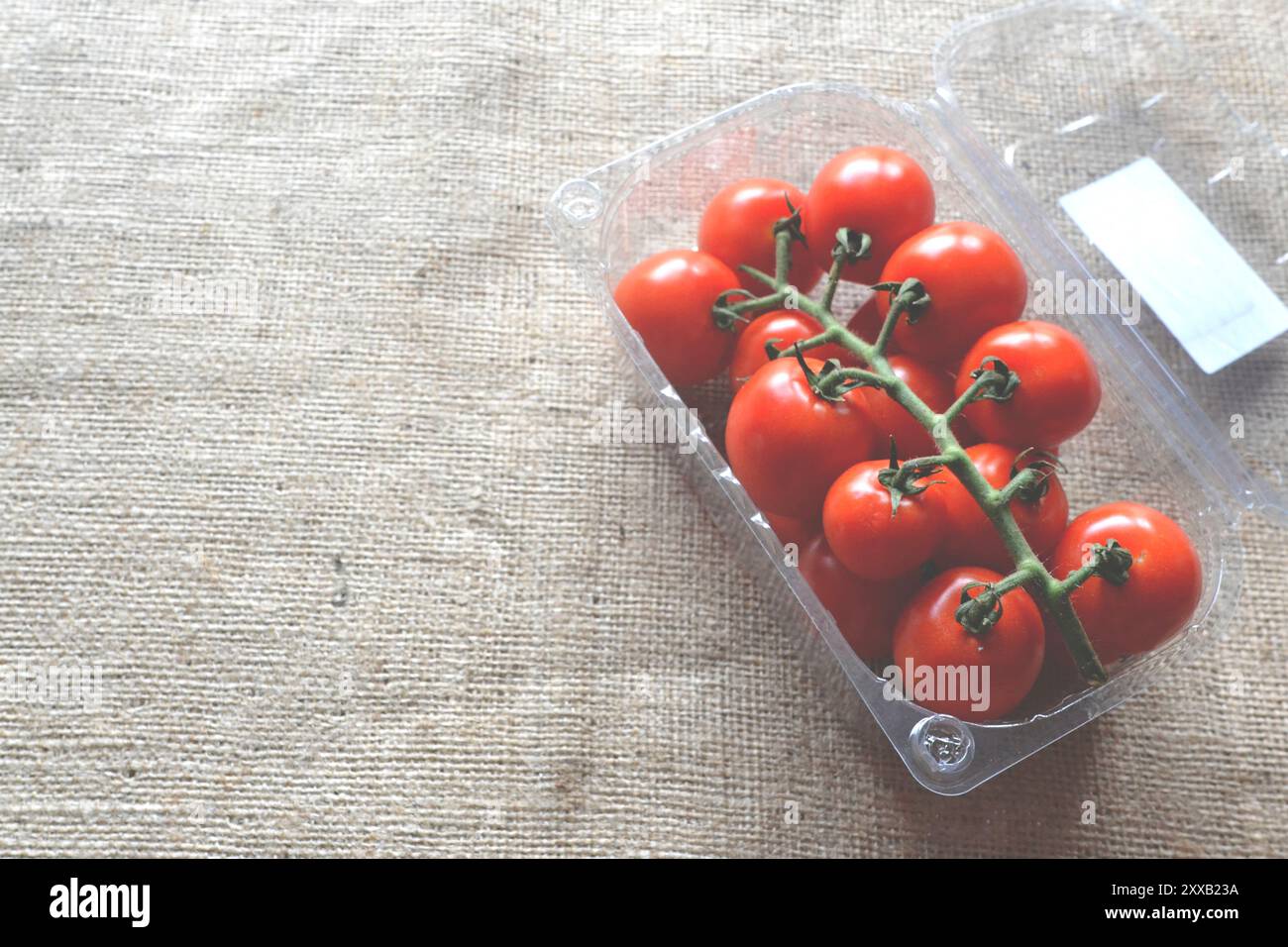 Tomatoes in a plastic packet on a jute background Stock Photo - Alamy