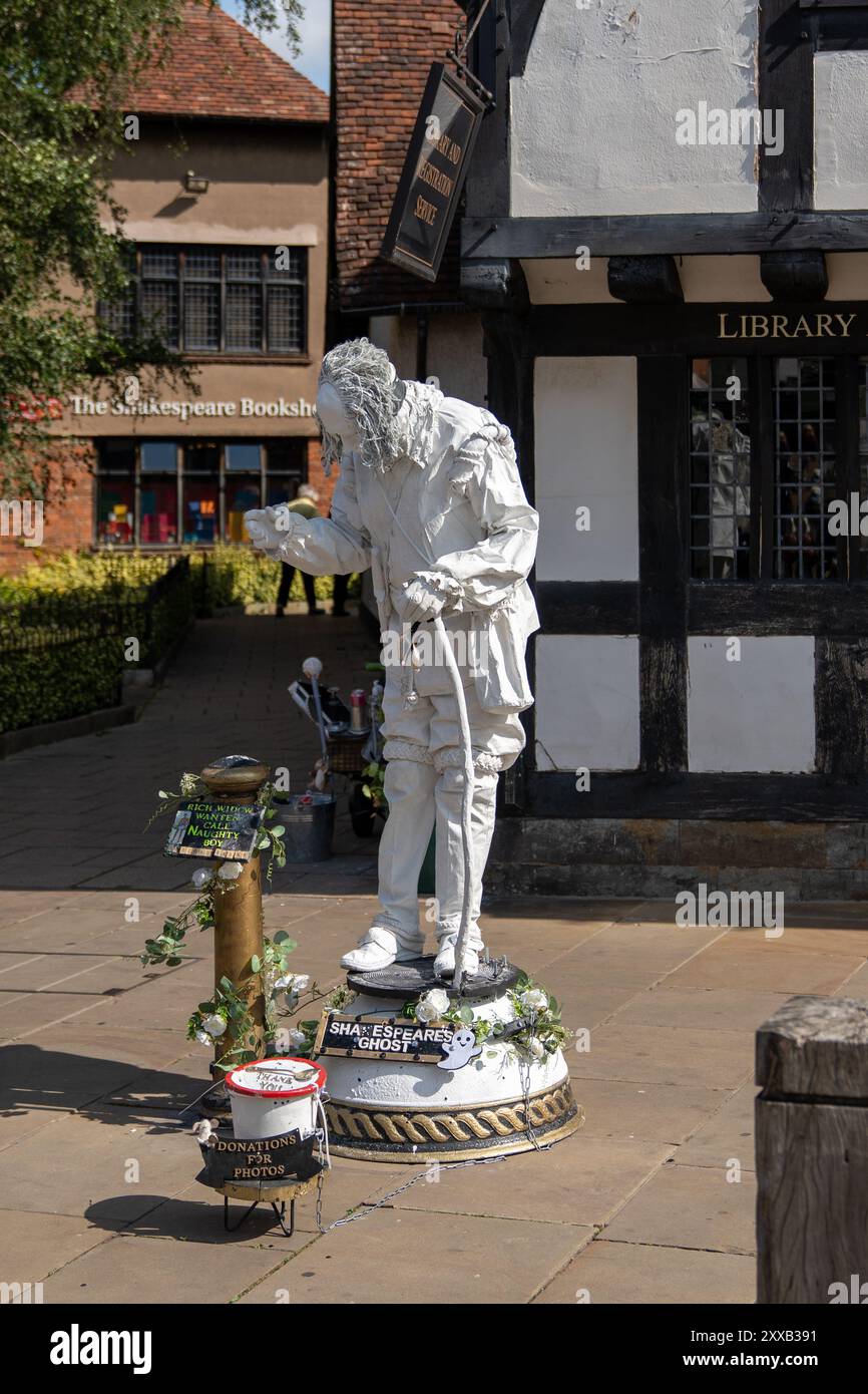 Street performer covered in white paint is posing on a pedestal ...