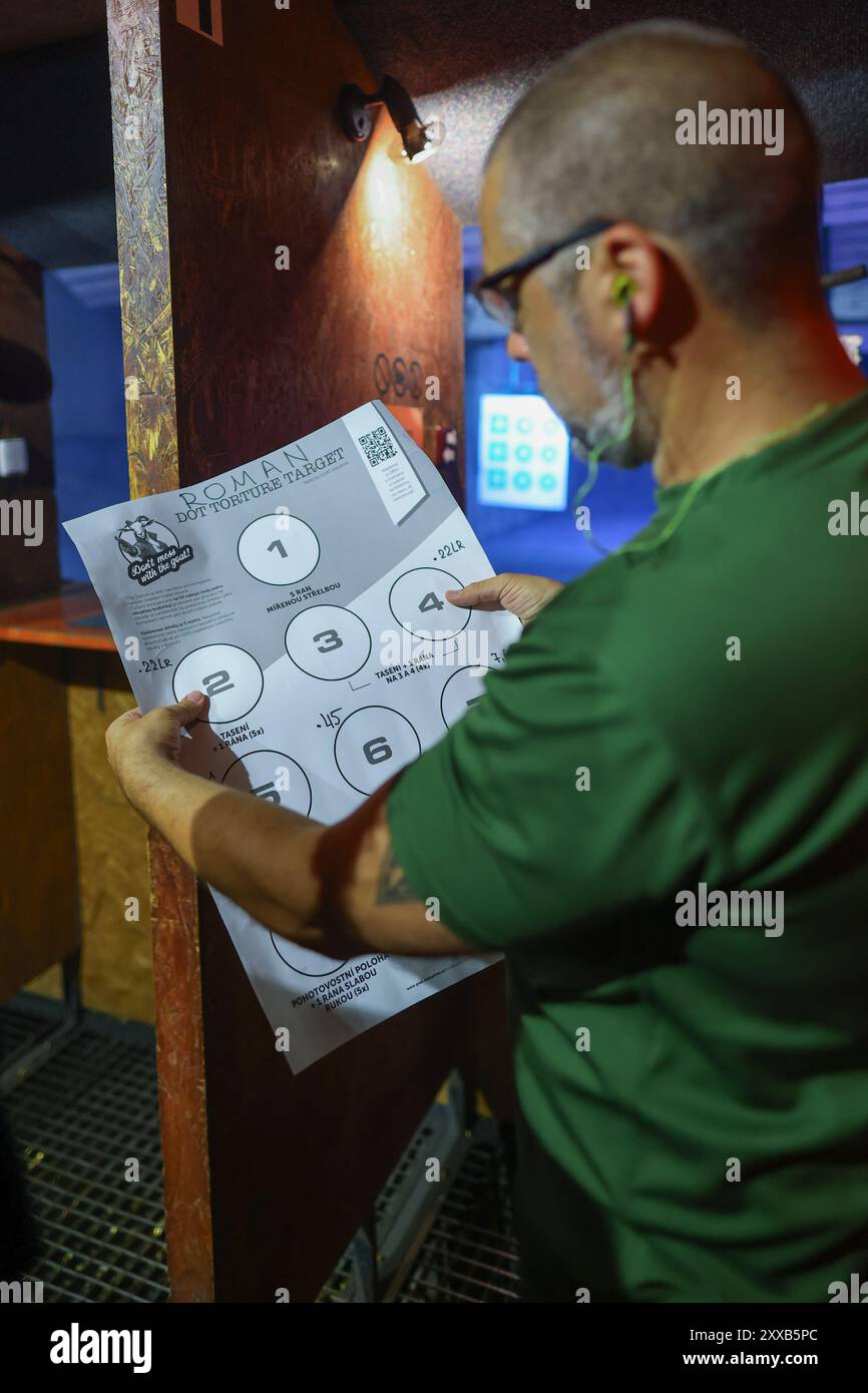 side view of shooter looking at used target after shooting in gallery ...