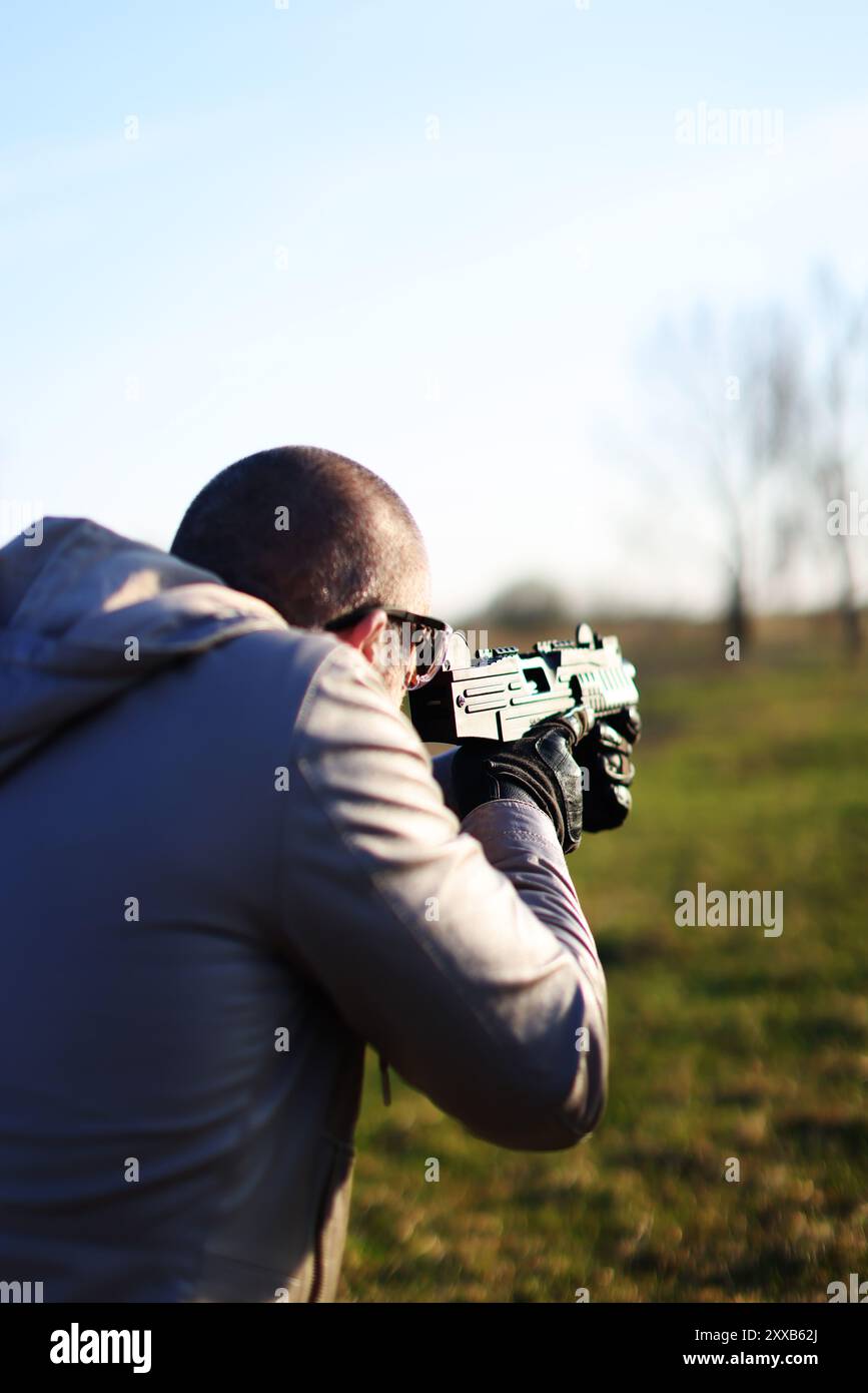 Man with gray jacket shooting black rifle on an openair shooting range ...